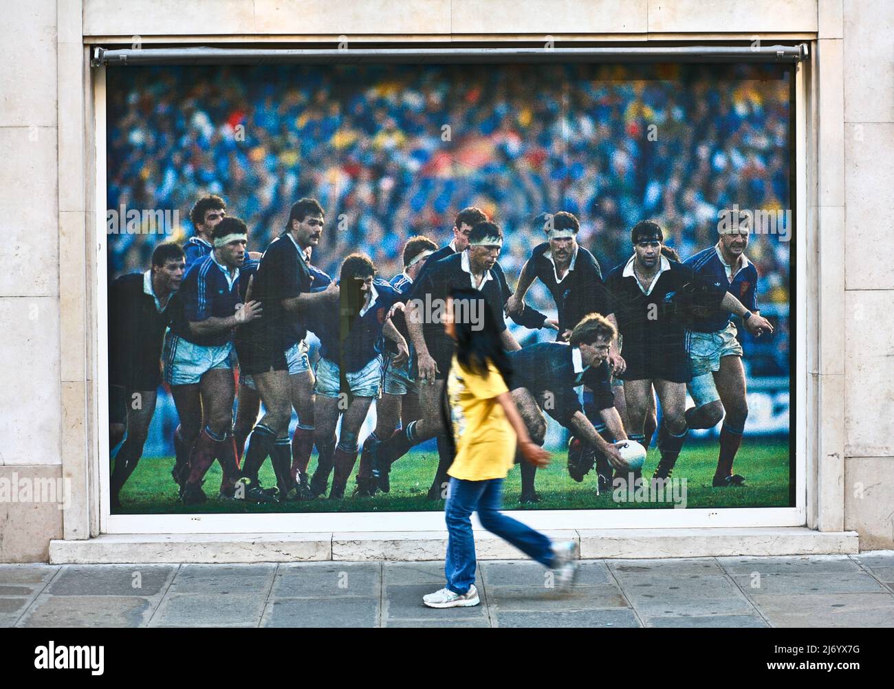 Paris, people passing by a large poster with the french Rugby team ...