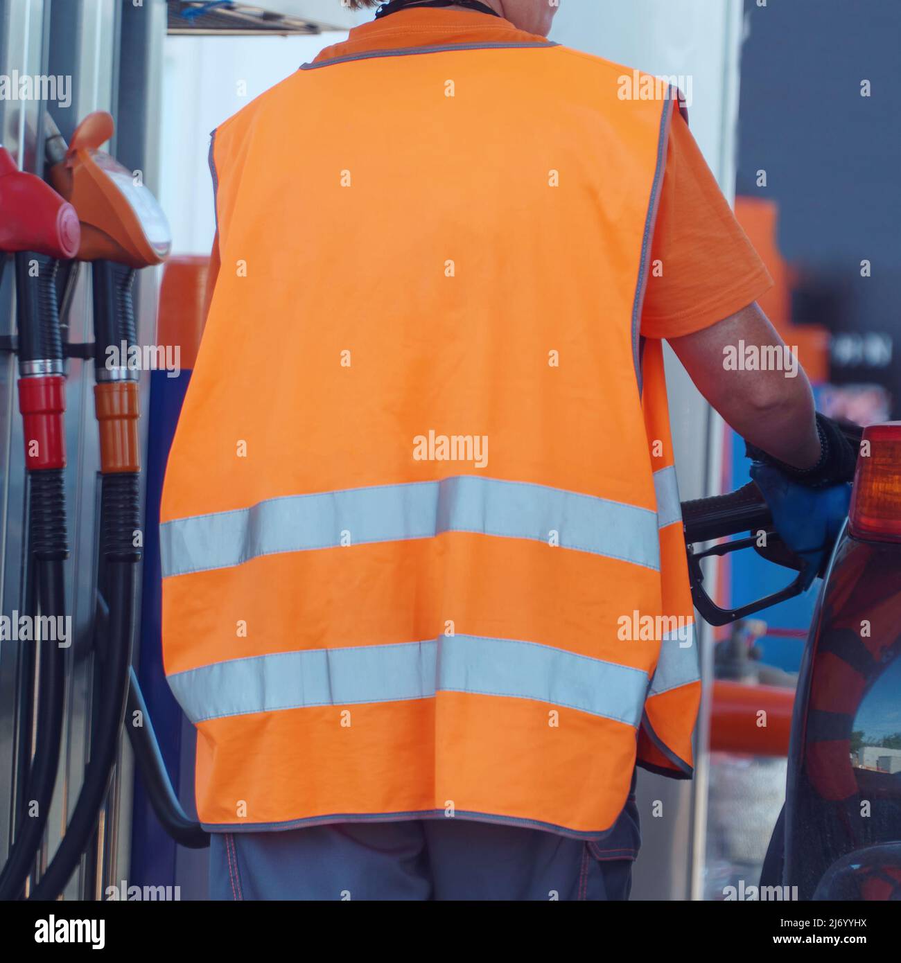 A worker in uniform at a petrol station. Refueler or petrol station ...
