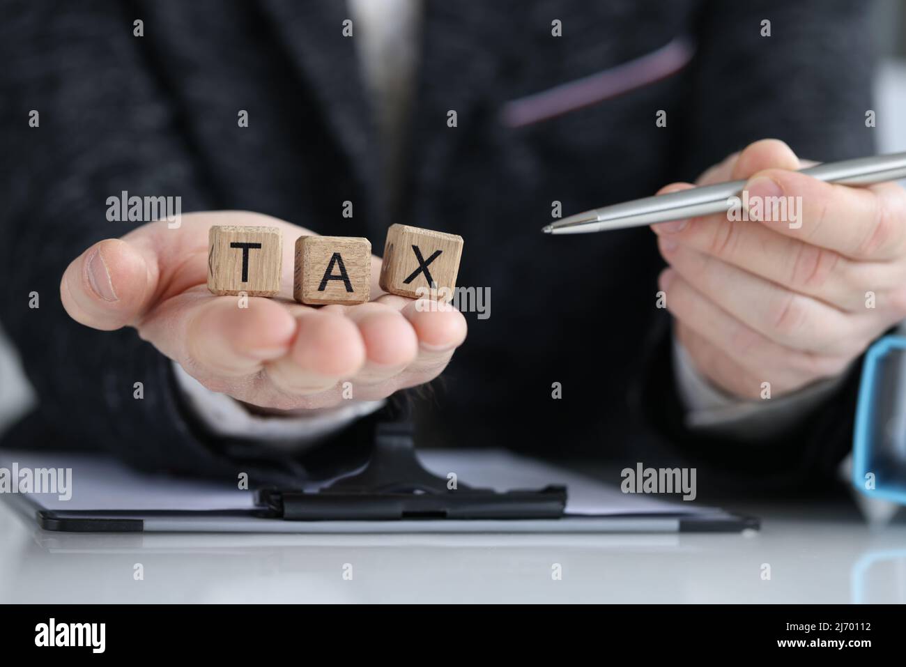 Tax text on wooden cubes and businessman with pen Stock Photo - Alamy