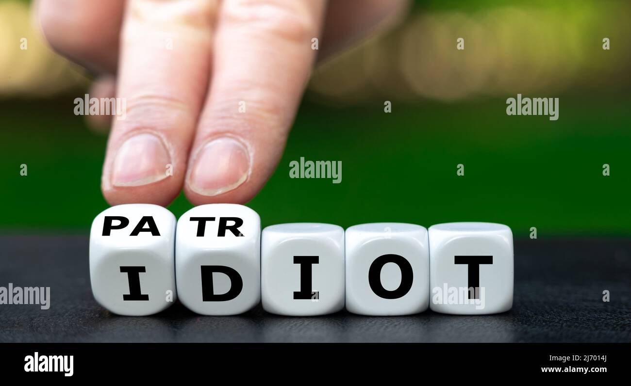 Hand turns dice and changes the word idiot to patriot Stock Photo - Alamy