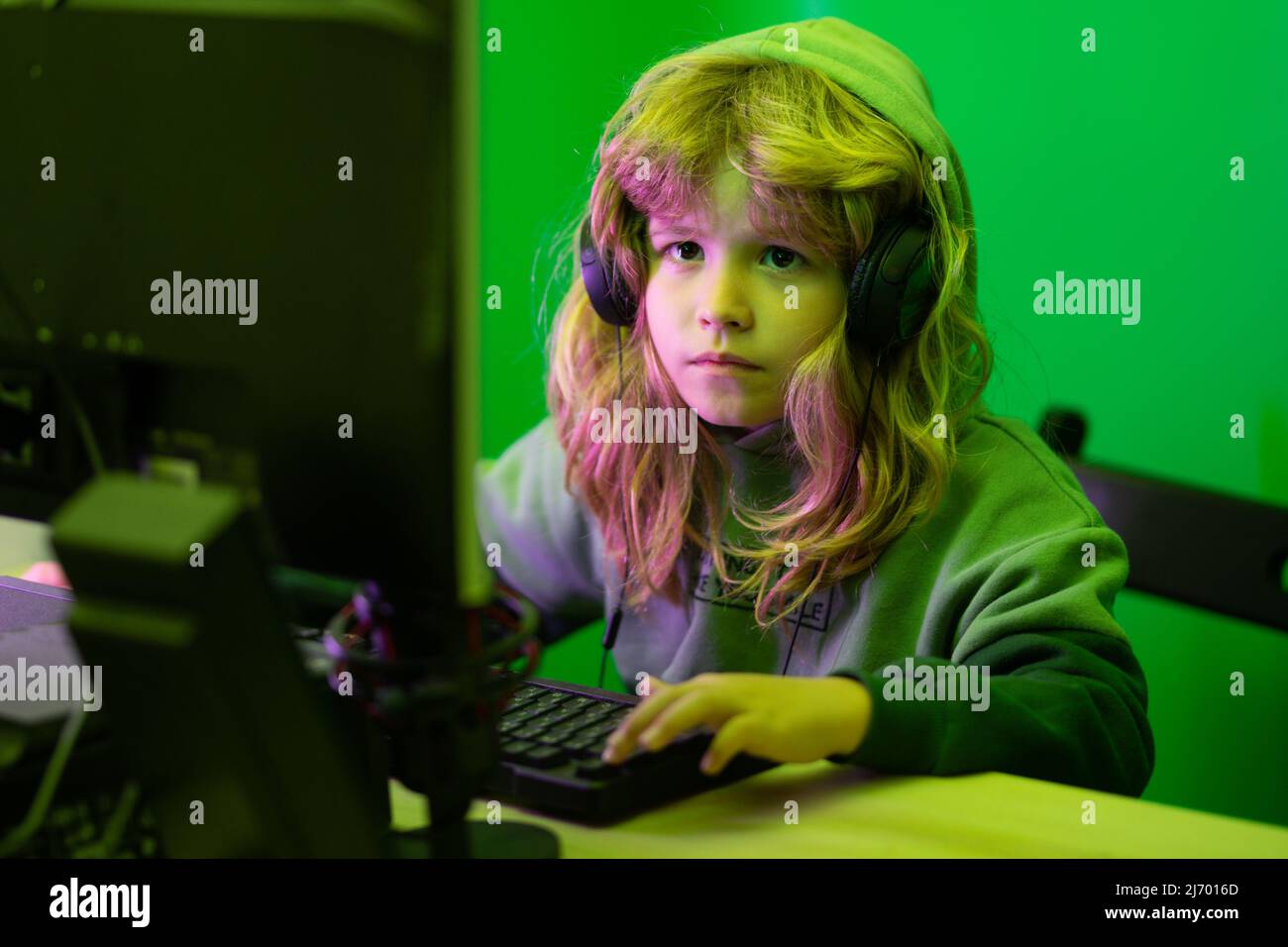 Child learning online at night, using desktop computer in living room ...