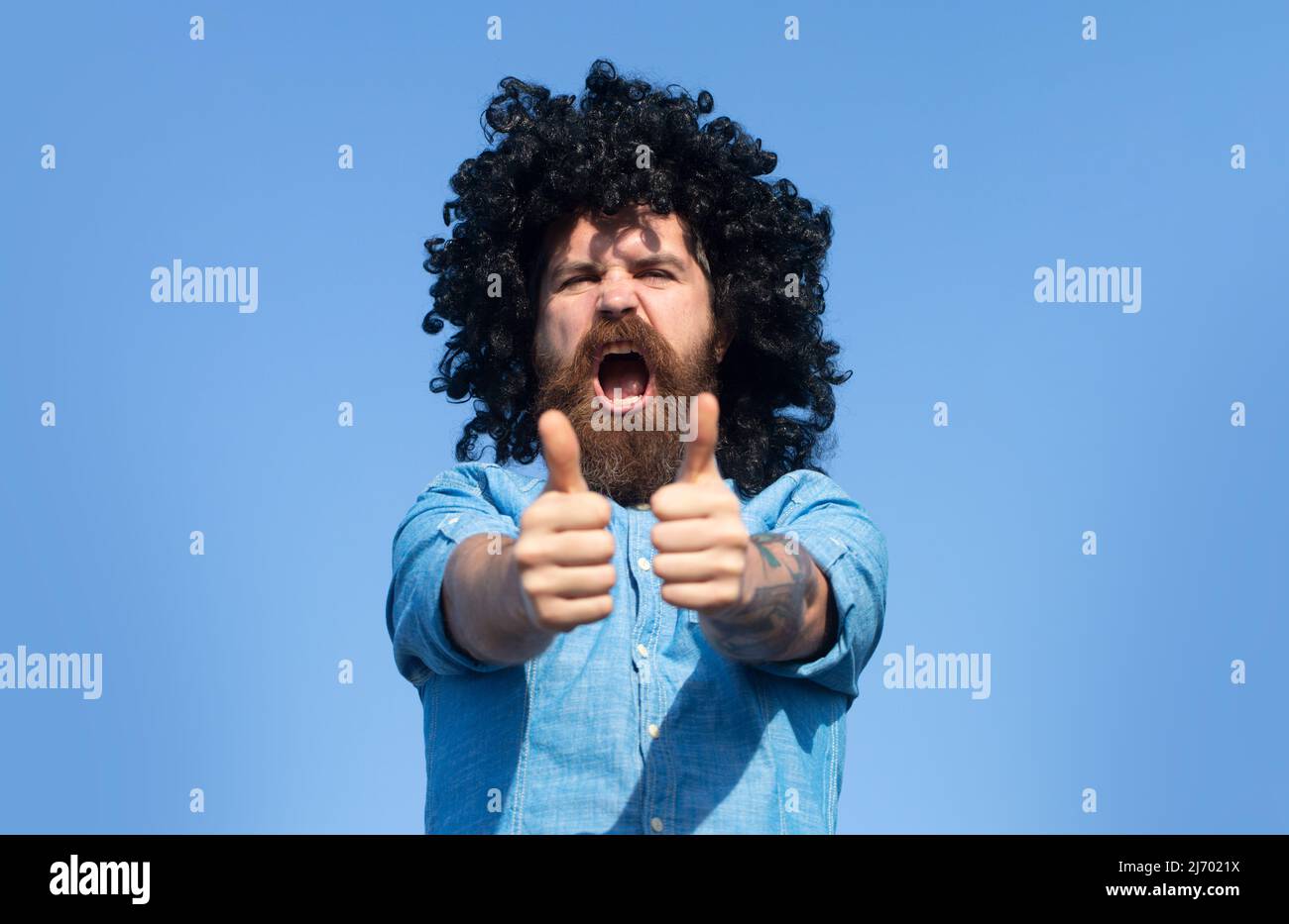 Funny nerdy guy with thumbs up. Crazy funny bearded man with wig on sky ...