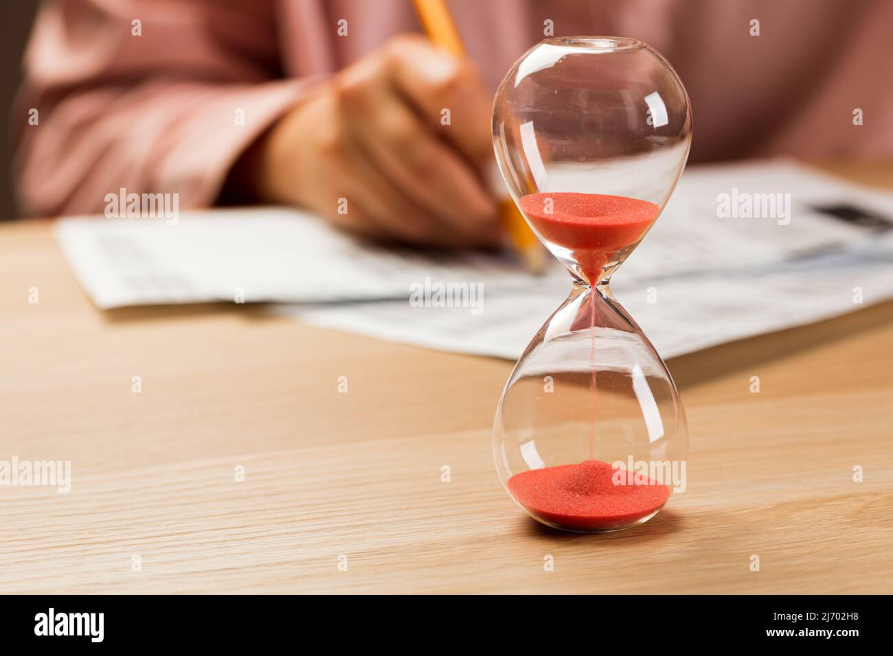 Hourglass with time running out and student hand testing in exercise ...