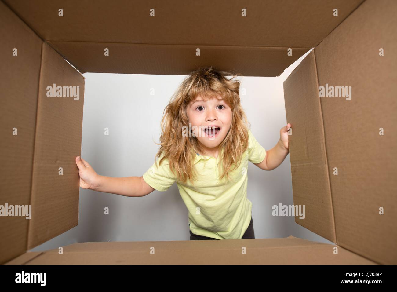 Child boy opening a carton box and looking inside, unpacking concept ...