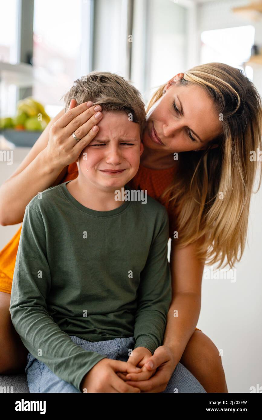 Portrait of mother consoling her crying sad injured son. Child family support parent concept ...