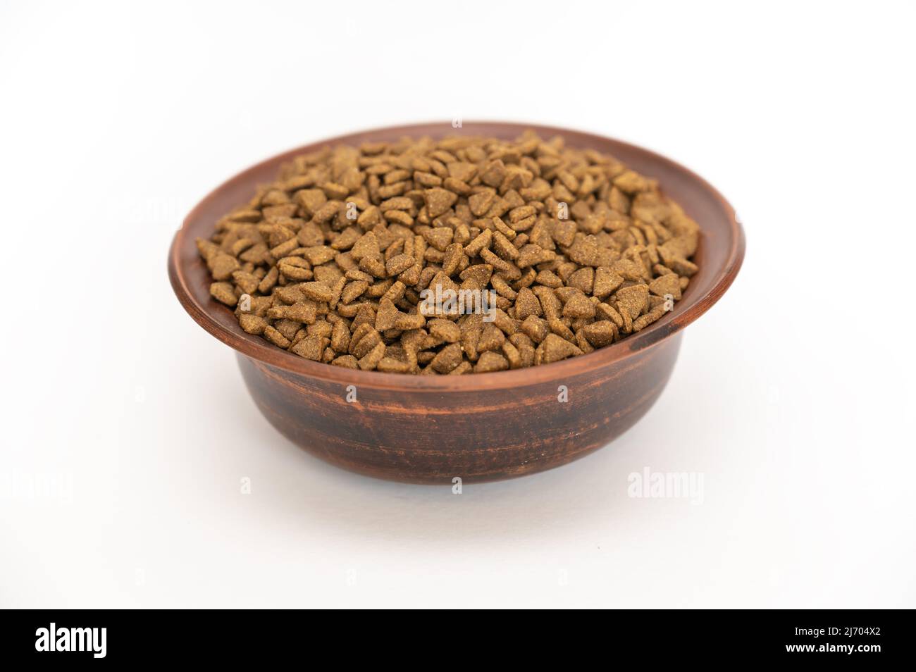 Pet food. Dry pelleted food in a brown clay bowl against a white ...