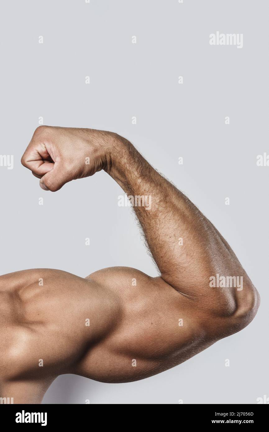 Muscular arm of young bodybuilder on gray background Stock Photo - Alamy