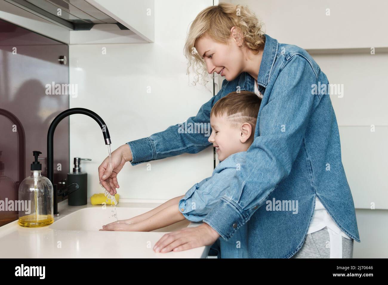 Young mother helping to her son during hand washing routine Stock Photo ...