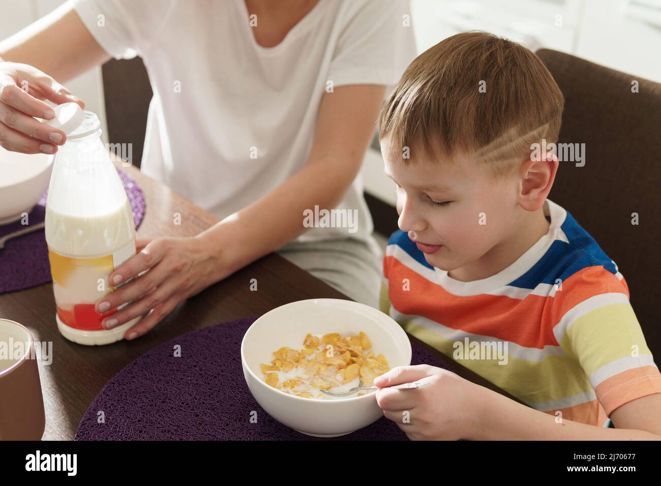 Beautiful mother and her cute son eating healthy cornflakes for ...
