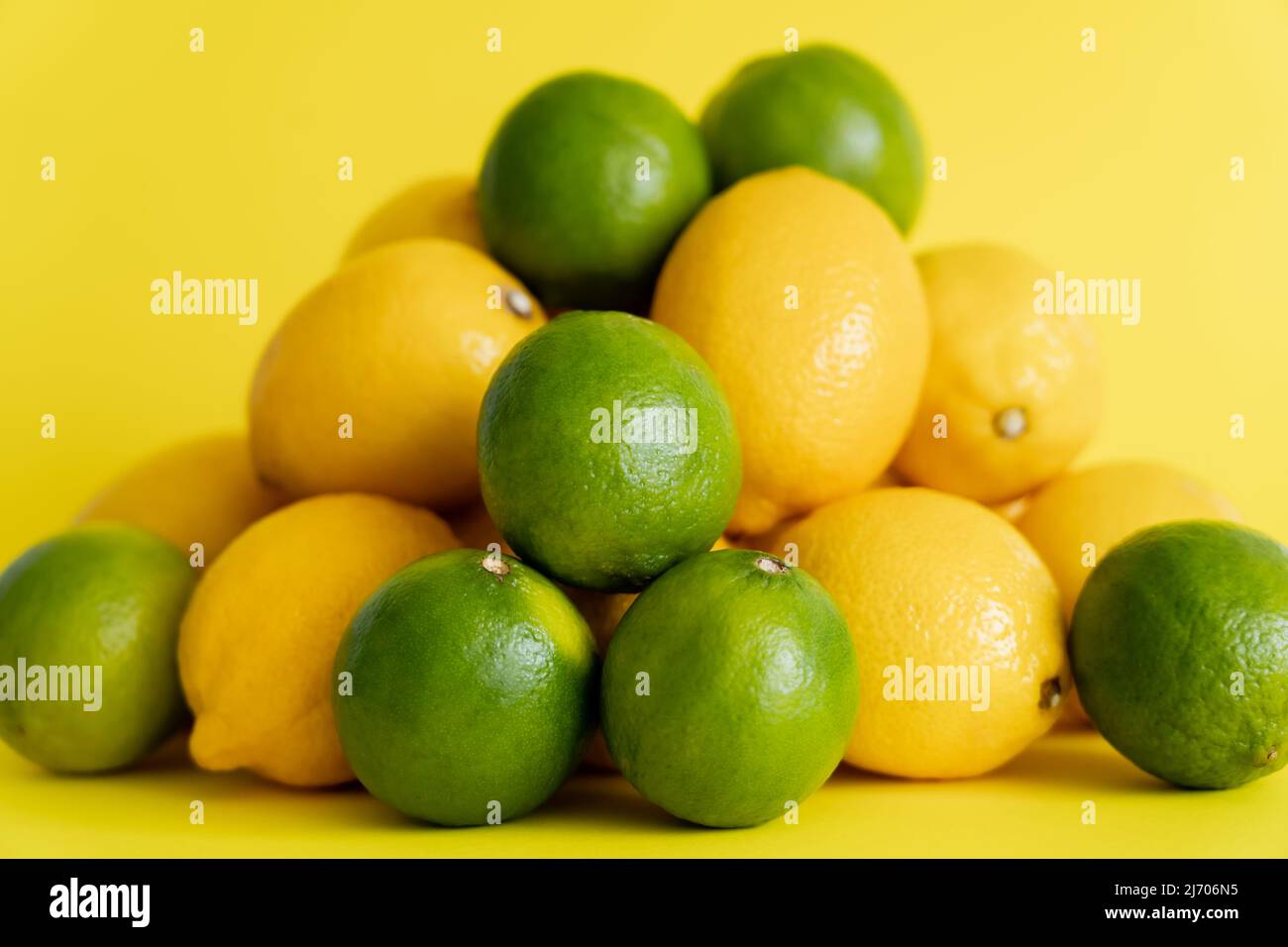 Juicy limes near heap of blurred lemons on yellow surface Stock Photo ...