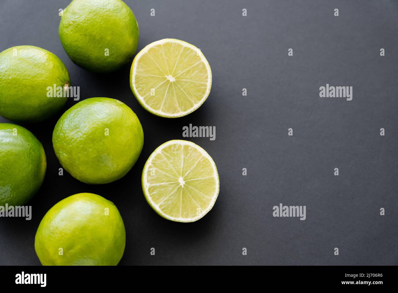 Top view of whole and cut limes on black background with copy space ...