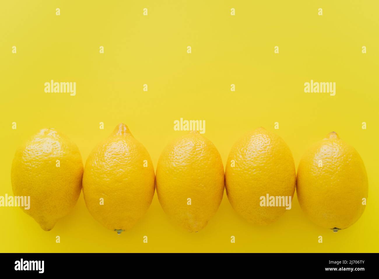 Top view of row of lemons on yellow surface with copy space Stock Photo ...