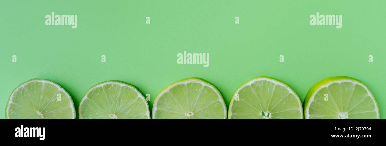 Top view of sliced lime on green background, banner Stock Photo - Alamy