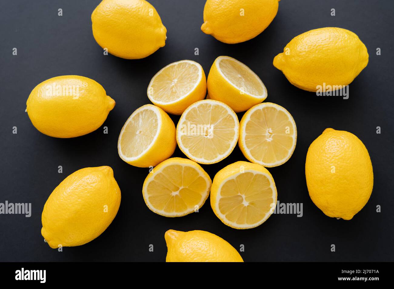 Flat lay with cut and whole lemons on black background Stock Photo - Alamy