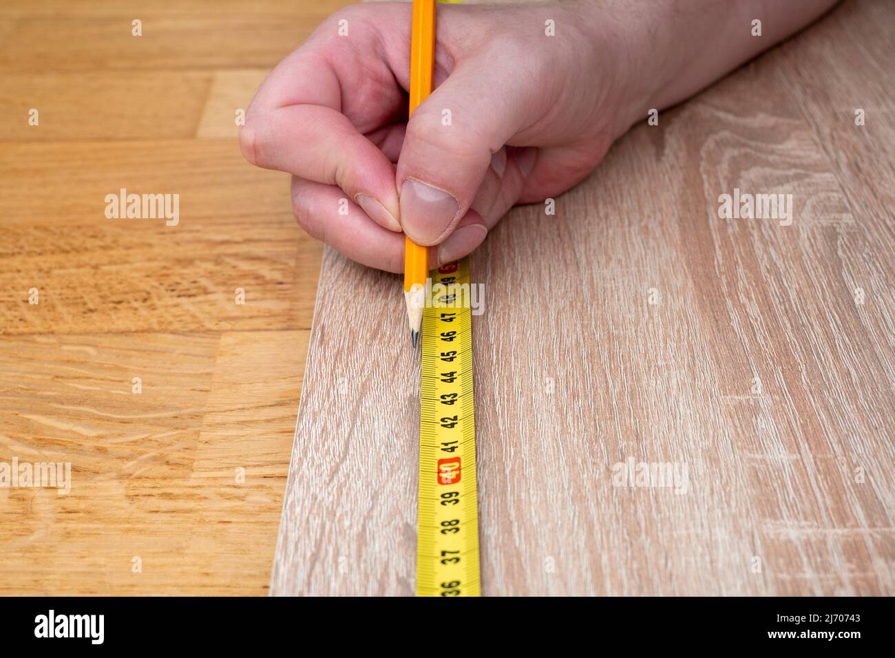 Close-up of hand of a carpenter measuring with a yellow ruler and ...
