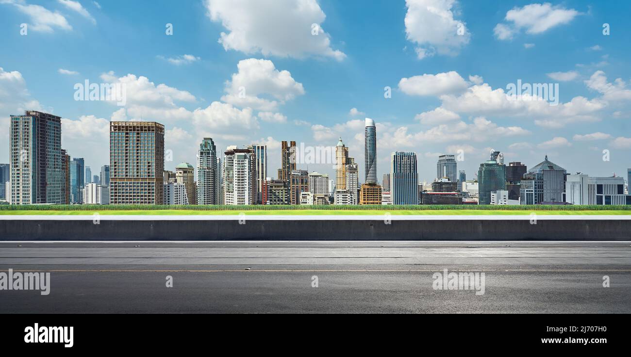Side view of asphalt road highway with green grass and modern city ...