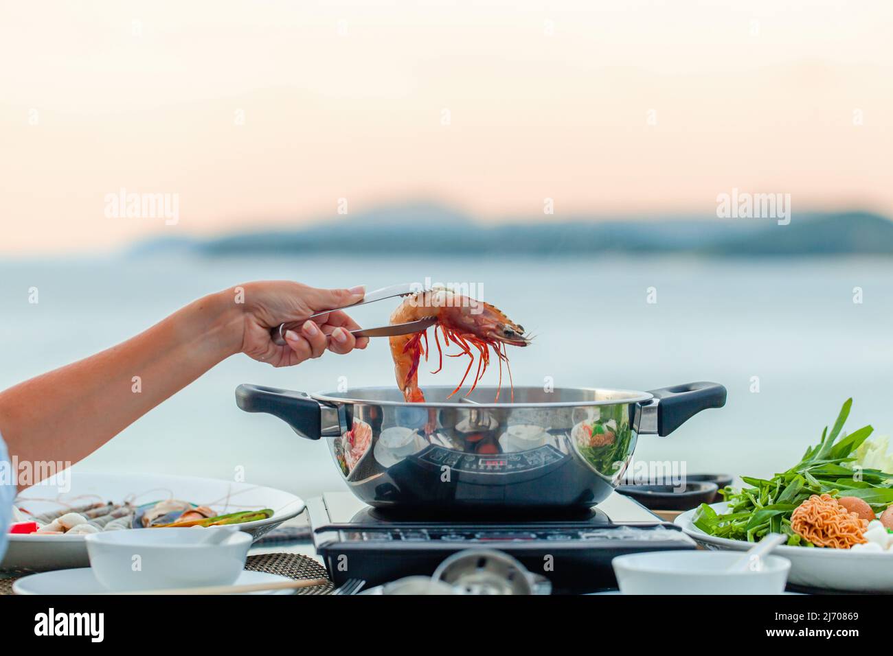 Woman hand take river prawn and put it in boiling pot Shabu shabu ...