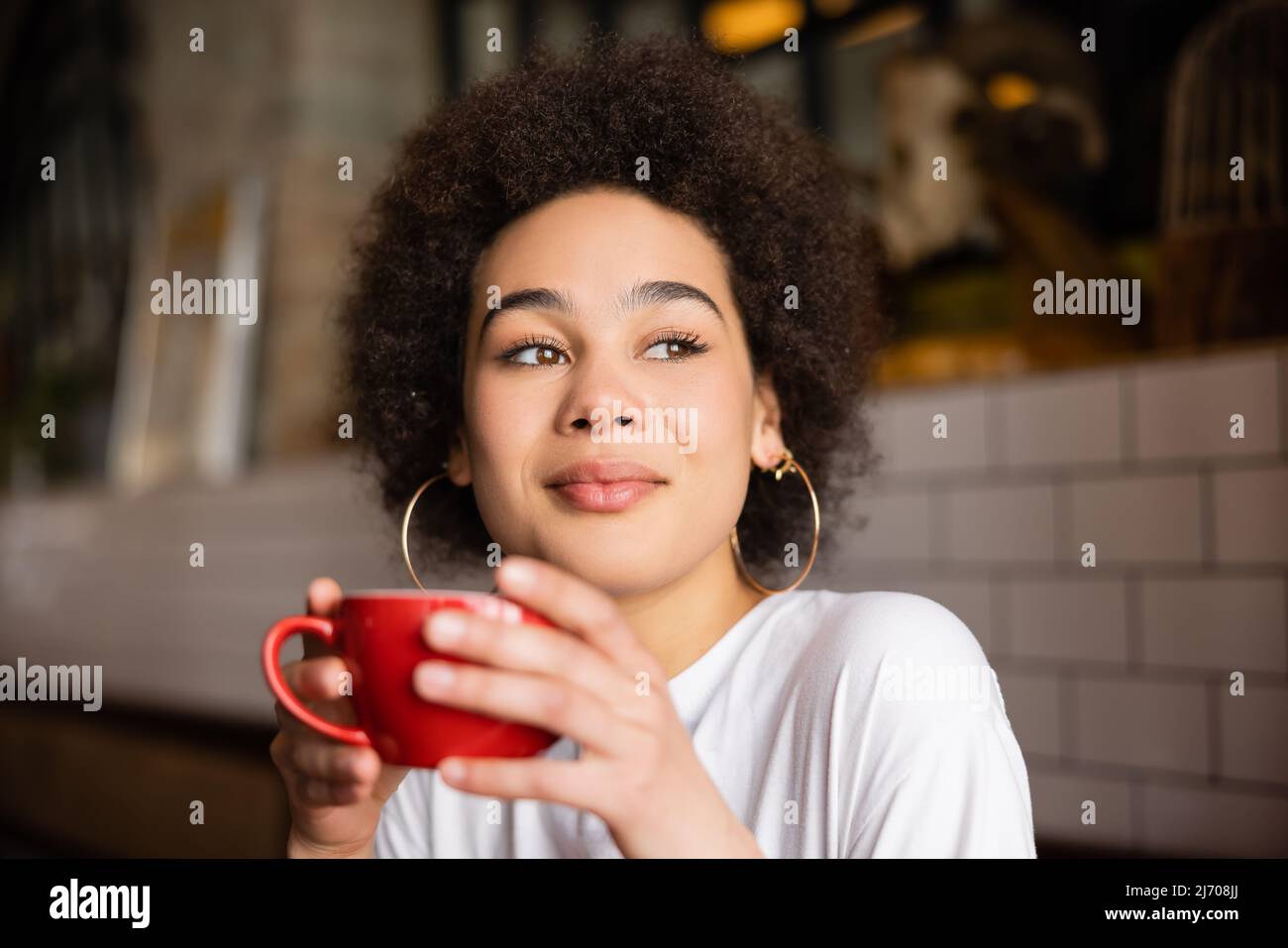 Pleased African American Woman In Hoop Earrings Holding Cup Of Coffee