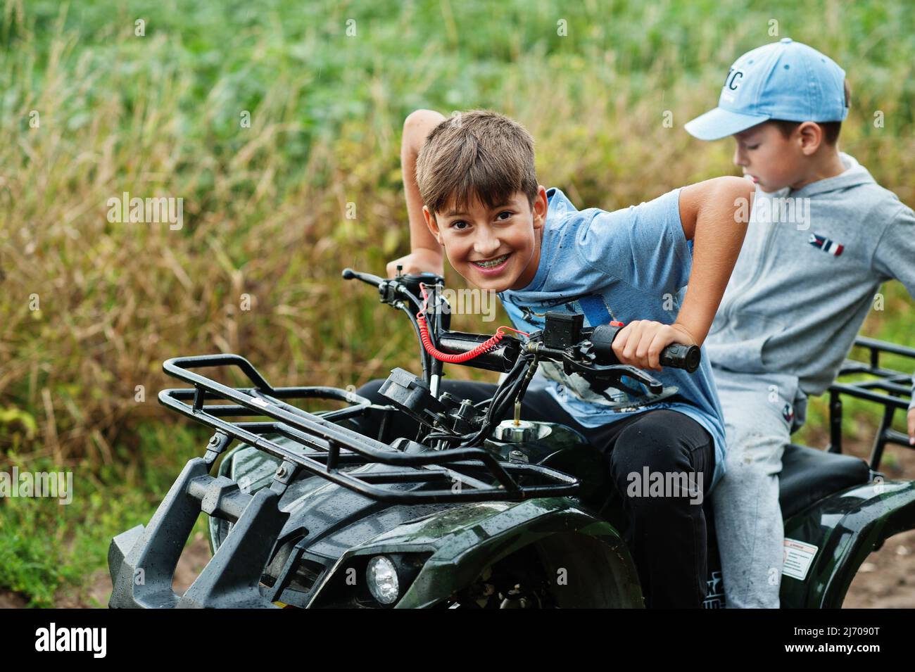 Two brothers driving four-wheller ATV quad bike. Happy children moments ...