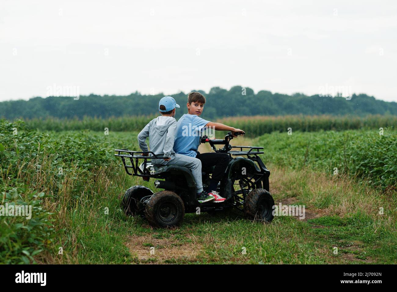 Two brothers driving four-wheller ATV quad bike. Happy children moments ...