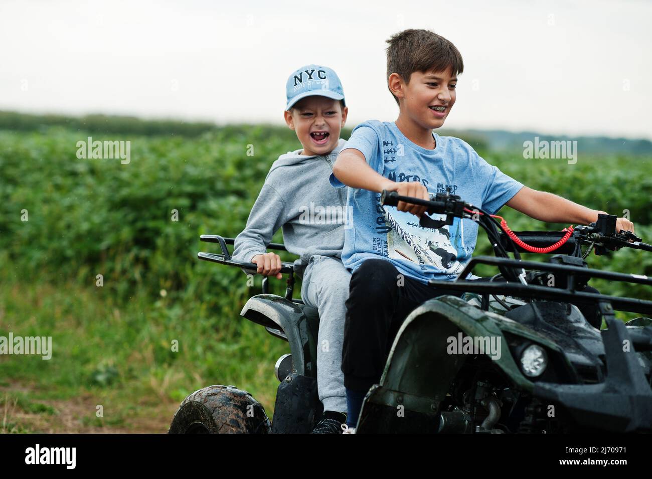 Two brothers driving four-wheller ATV quad bike. Happy children moments ...