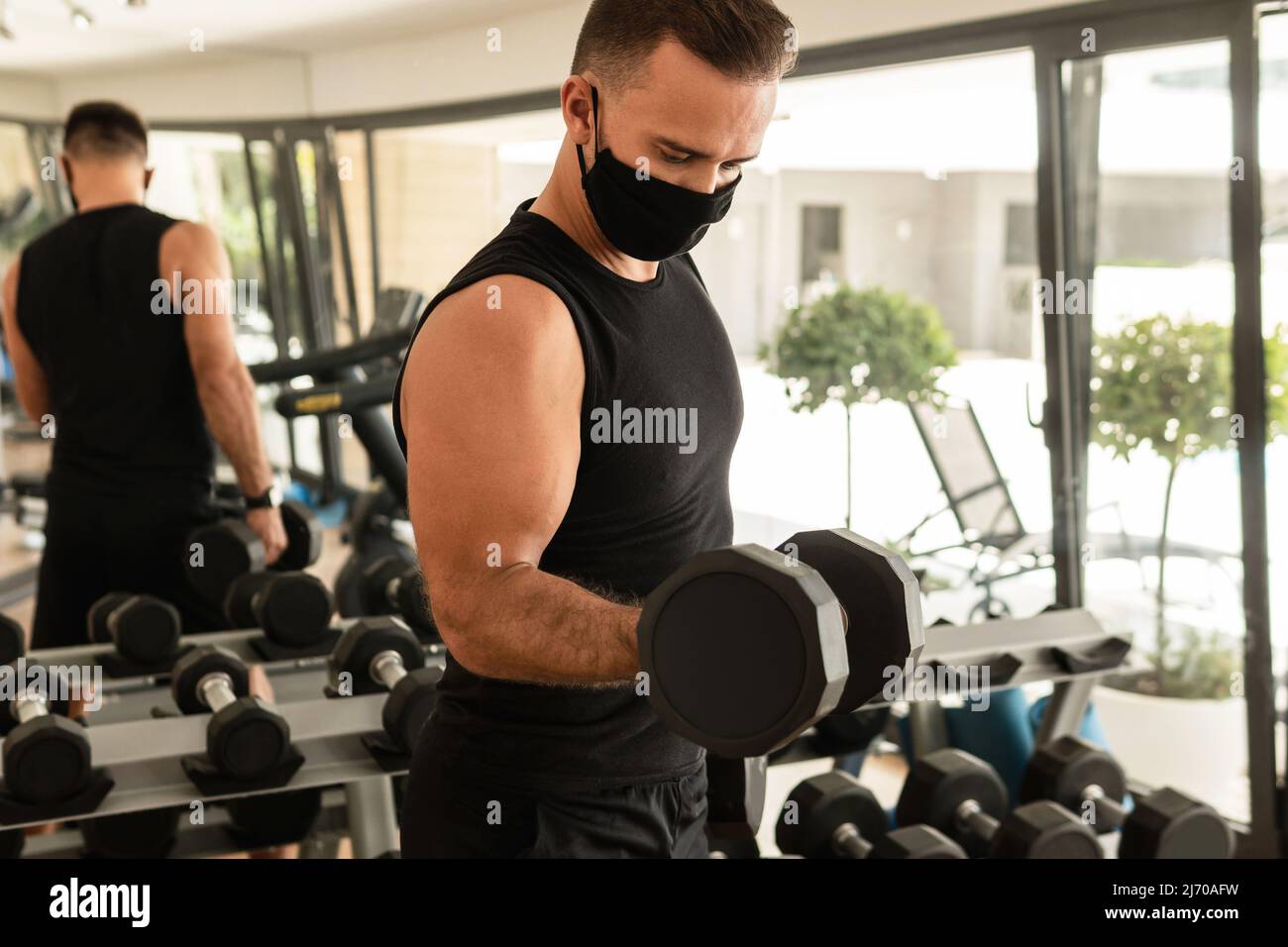Young athletic man wearing a prevention face mask during his workout in ...