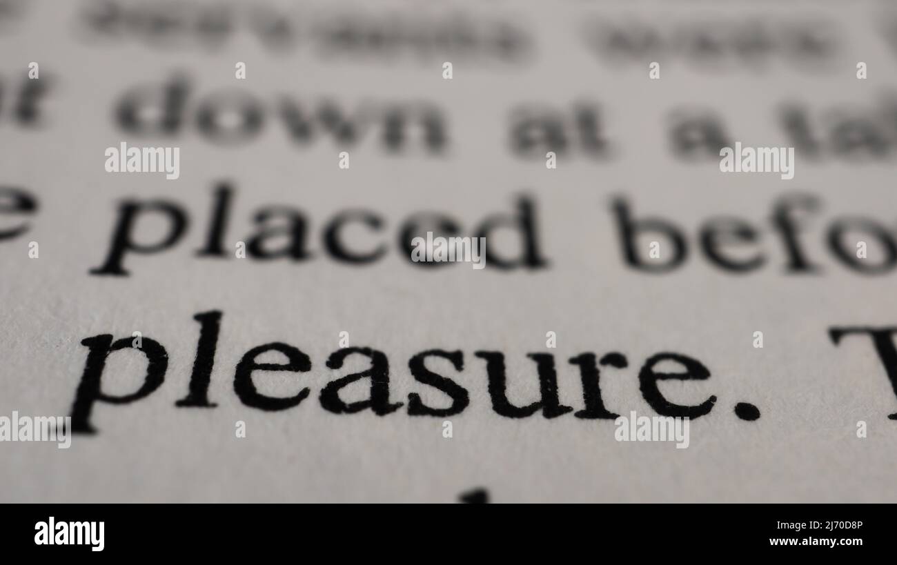 Pleasure text in open book page, selective focus, close up, macro shot ...