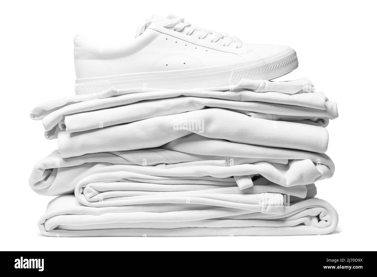 Stack of white clothes and stylish trainers white background Stock ...