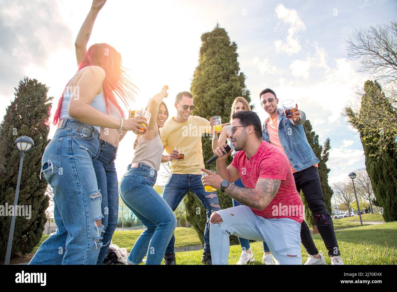 young man singing with microphone with his group of friends dancing at ...