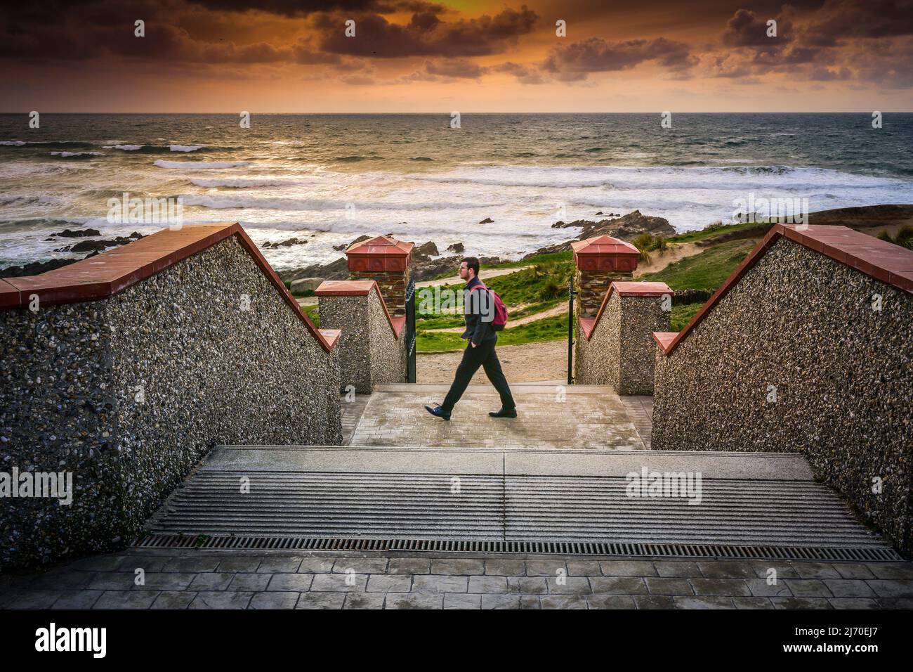 A man walking past the Headland Hotel steps leading down to the coast ...