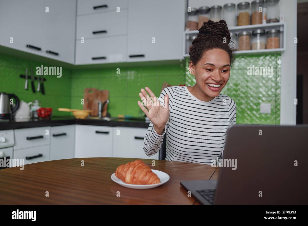 Smiling happy female waving hand looking at computer screen during ...