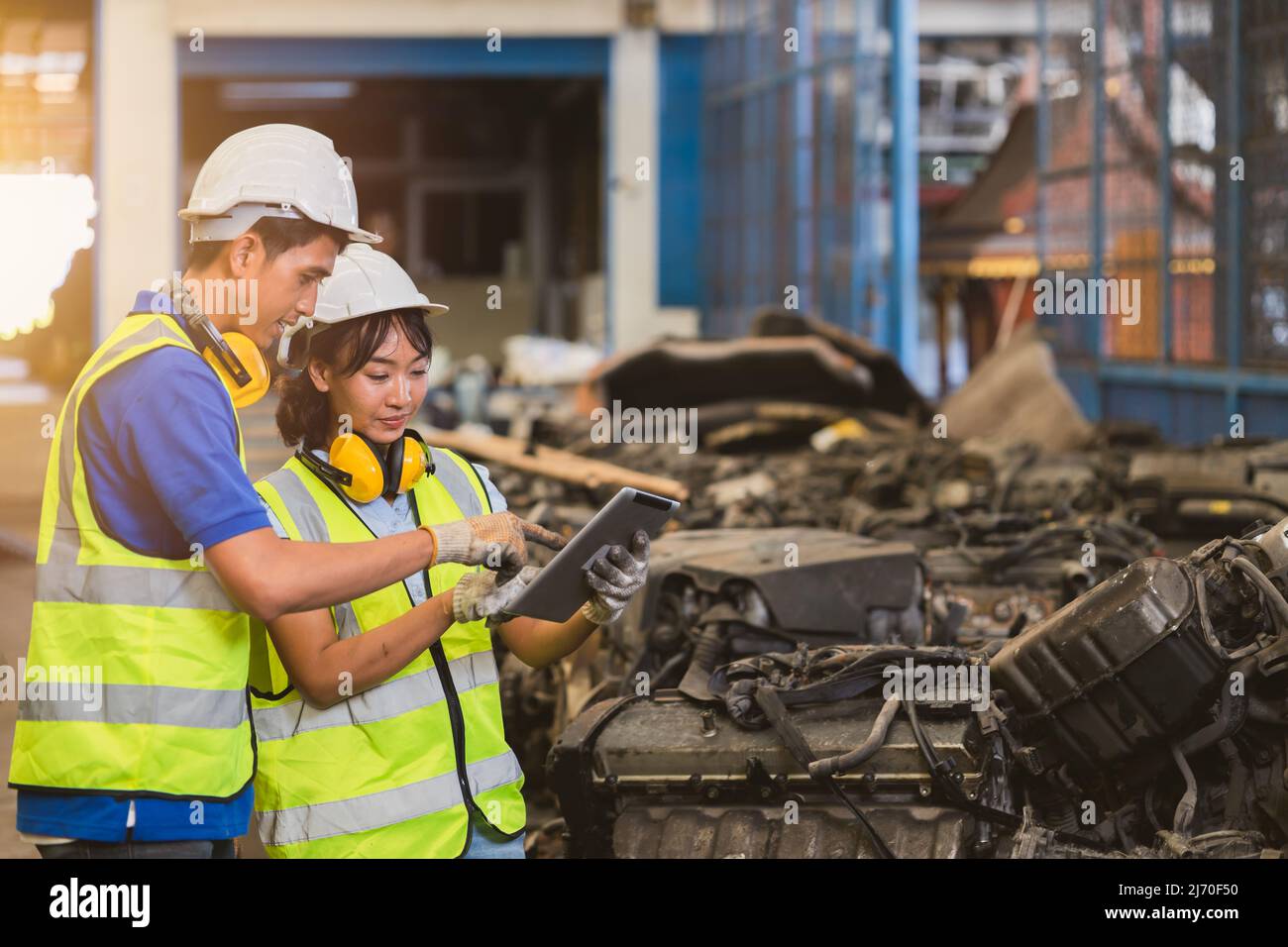 Young Asian man and woman staff worker working in dirty engine block ...