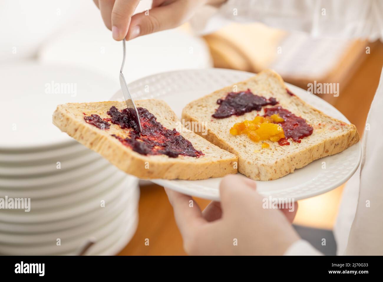 hand apply sweet berry fruit jam on a sliced whole wheat bread for ...