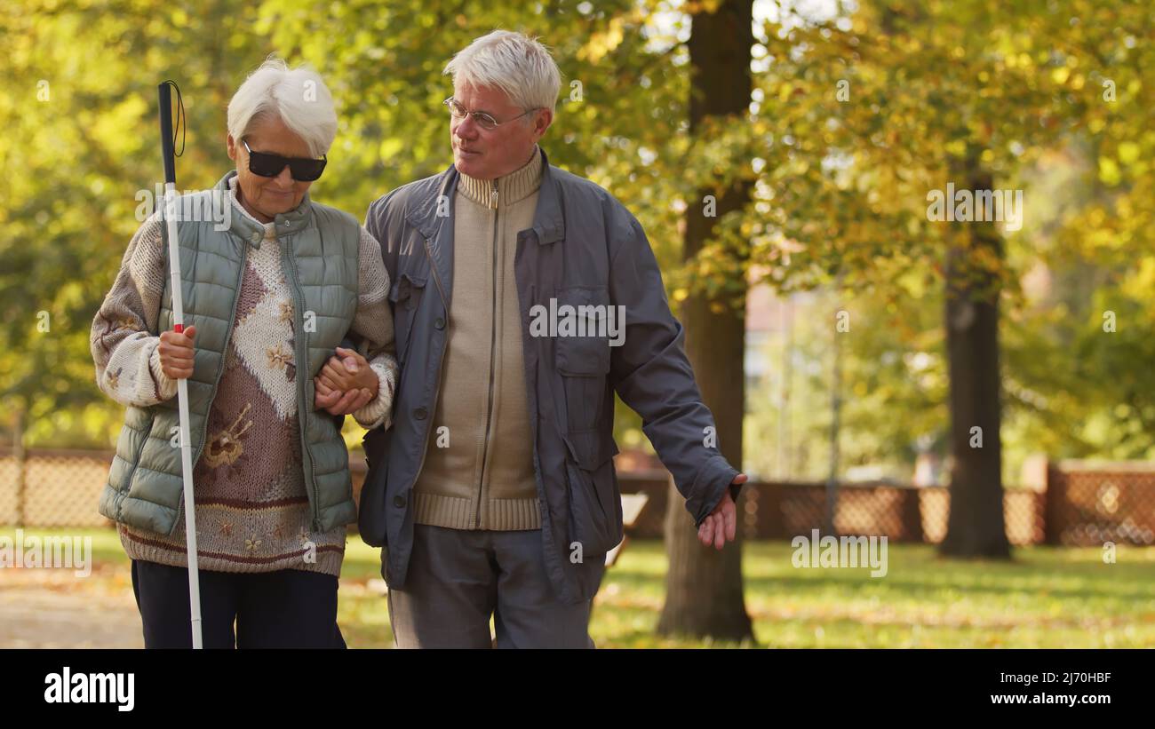 Life with disability. Elderly couple taking a walk in their favourite ...