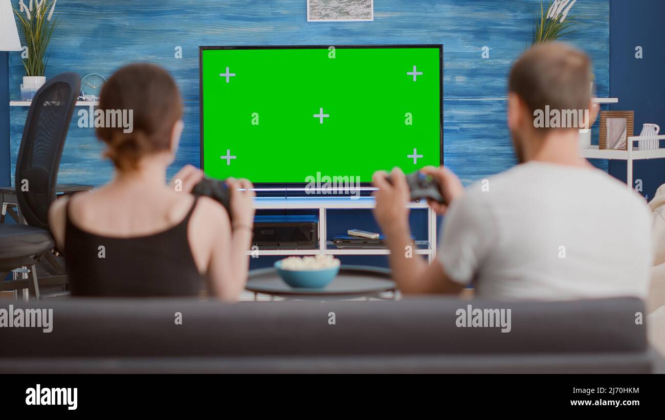 Couple holding controllers playing console online games on green screen ...
