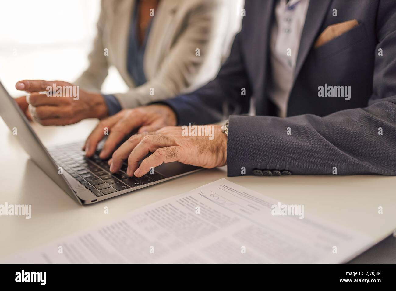 Female colleague aiming at laptop, Senior entrepreneur typing on ...