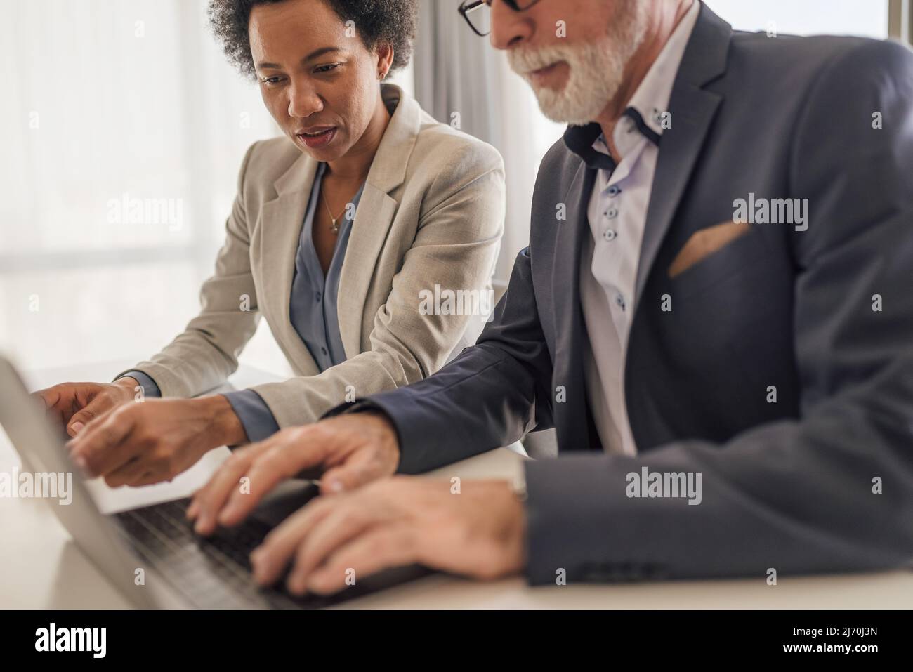 Female colleague explaining while aiming at laptop, Senior business ...