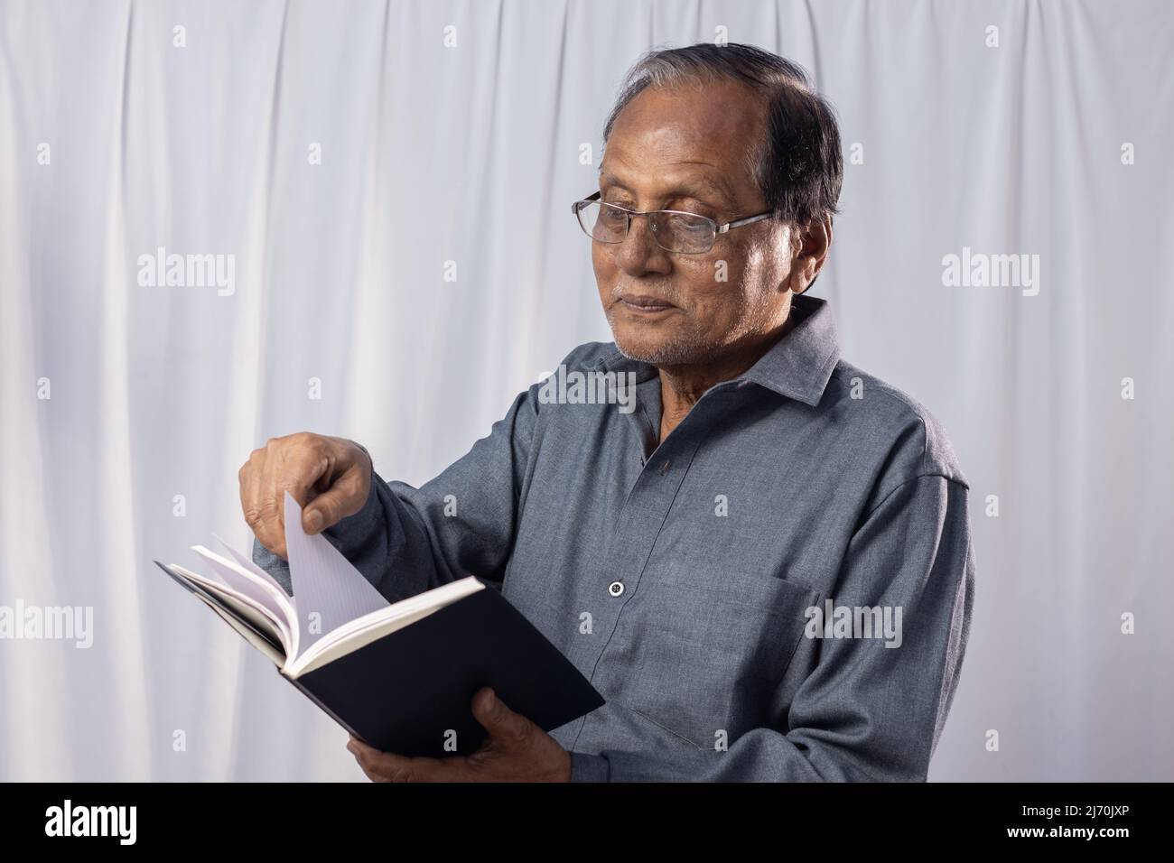 An old Indian man is reading books standing on white background Stock ...