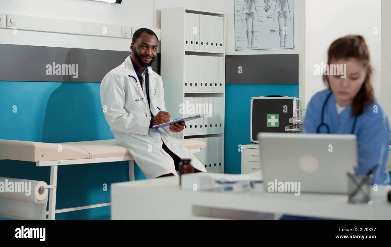 Portrait of general practitioner with checkup files in cabinet waiting ...