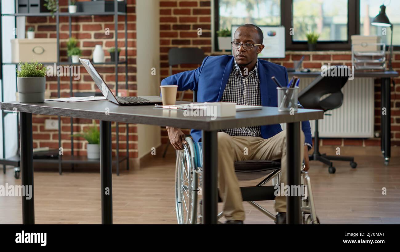 Paralyzed worker with physical disability analyzing statistics on ...