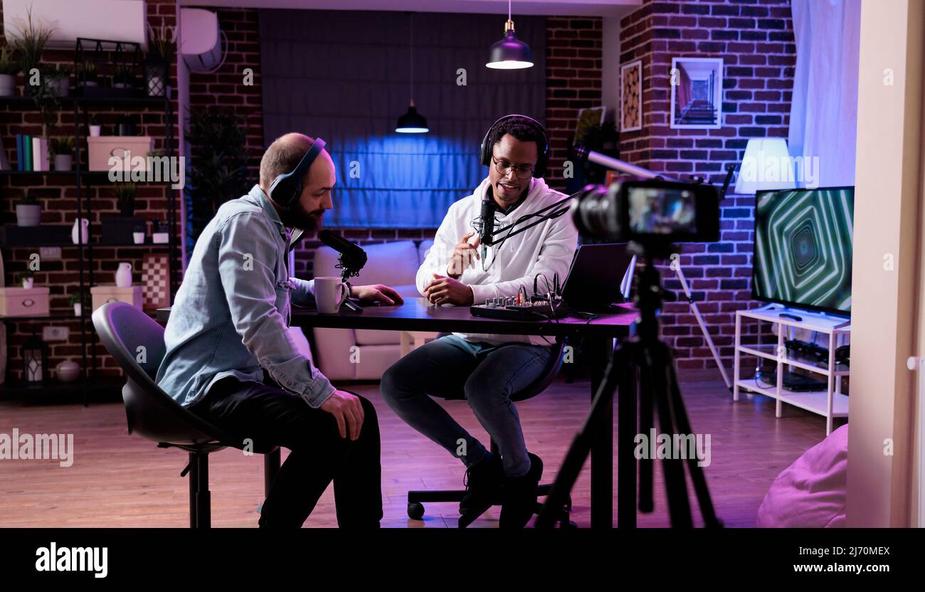 Online vlogger filming podcast episode with man in studio, using camera ...