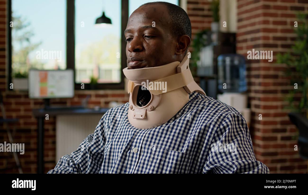 Office worker in pain working with medical neck collar foam at desk ...