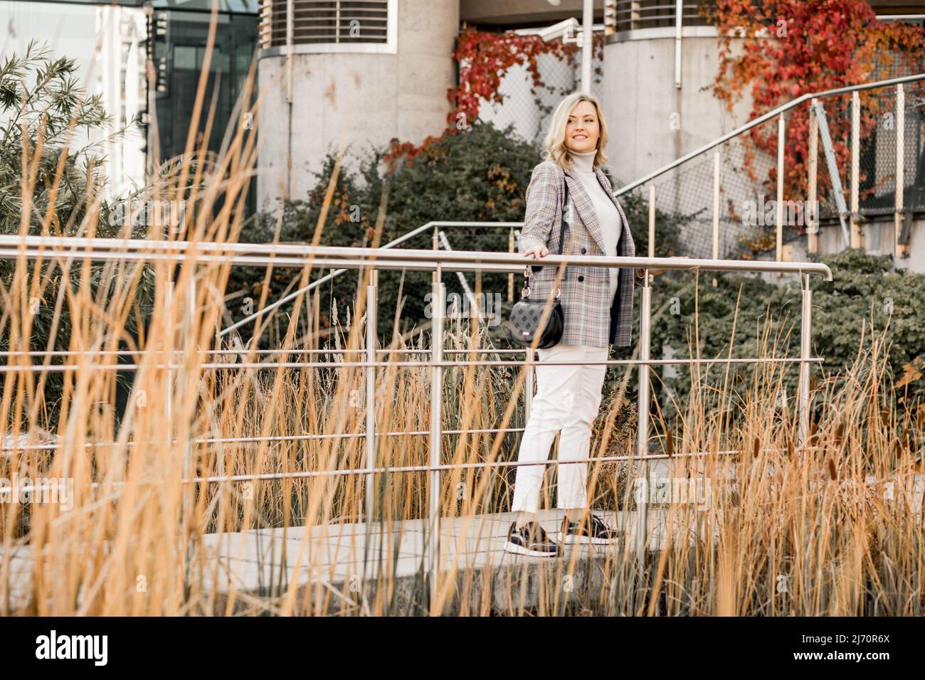Beautiful happy woman enjoying going along path in autumn city park ...