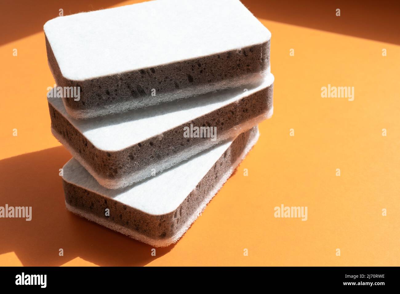 Three grey kitchen sponges on the orange background Stock Photo - Alamy