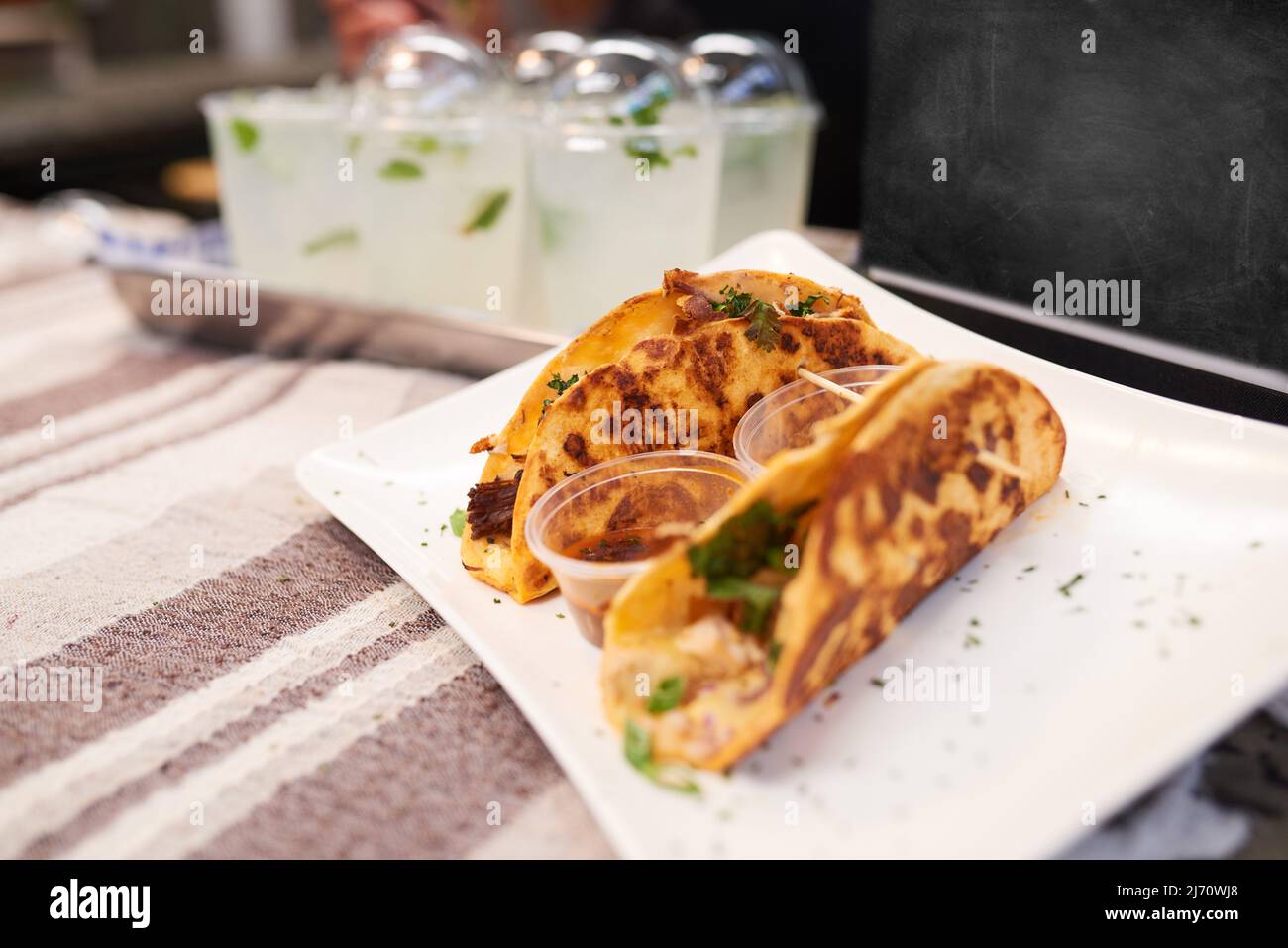Two soft shell tacos with a chalkboard and lemonade at a market stall ...