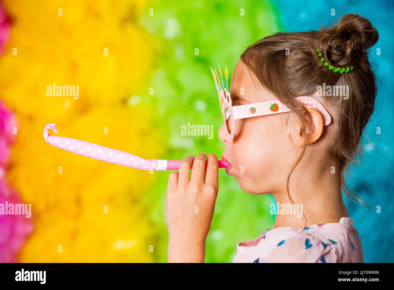 Cute girl celebrating birthday, wearing party paper glasses, blowing ...