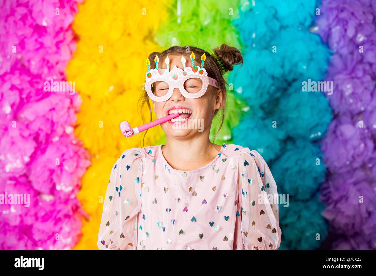 Cute girl celebrating birthday, wearing party paper glasses, blowing ...