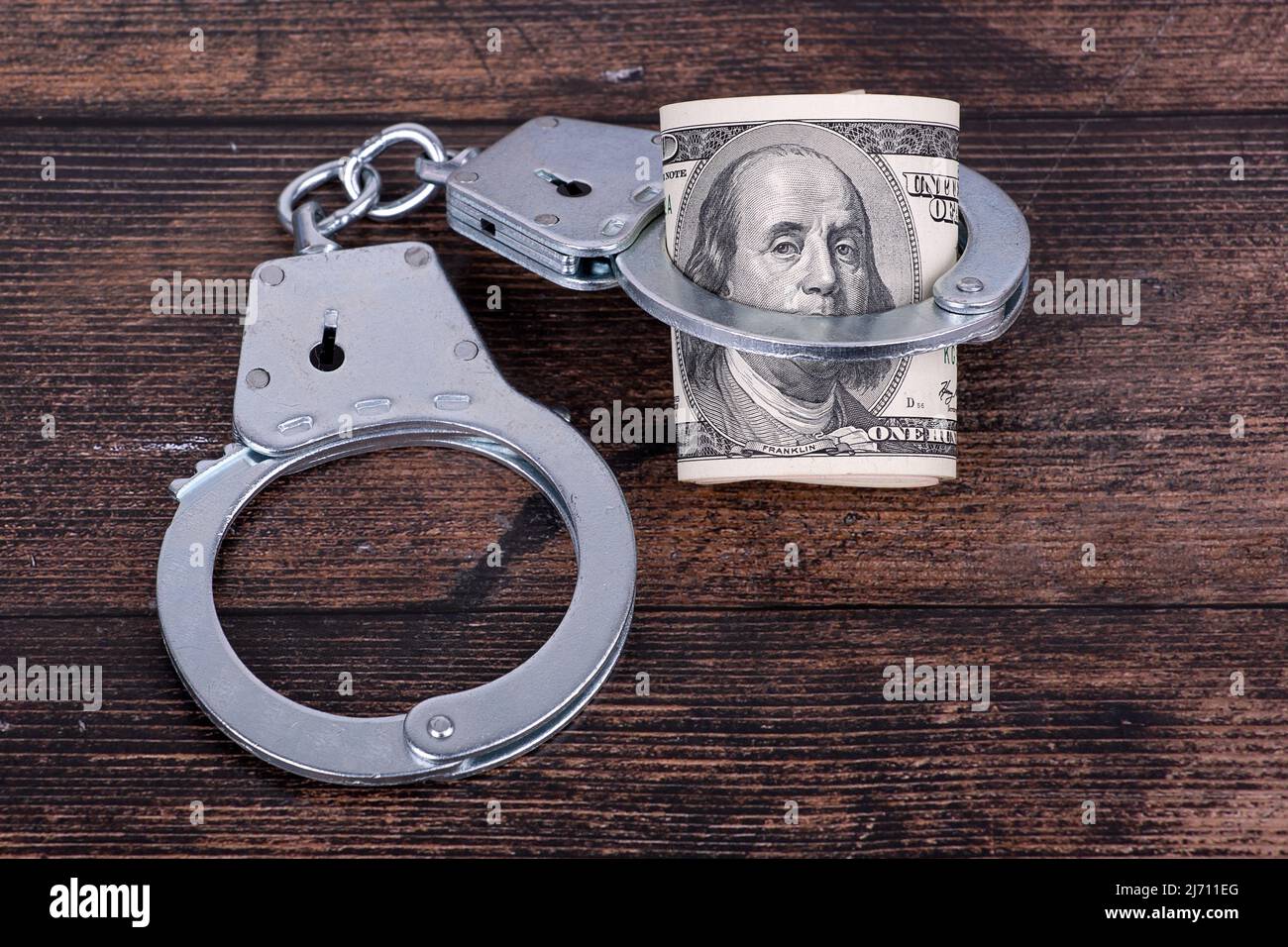 A wad of dollars inside the handcuffs. Benjamin Franklin in a ring of ...
