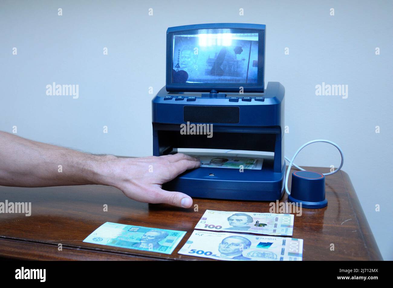 Man hand switching money detector on, banknote placed on receiver Stock ...