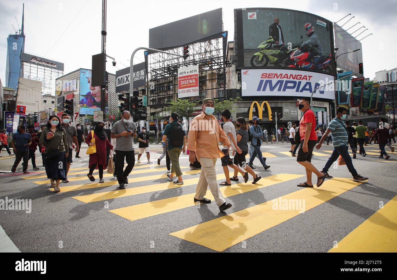Pedestrians wearing face masks are seen crossing the street near a ...